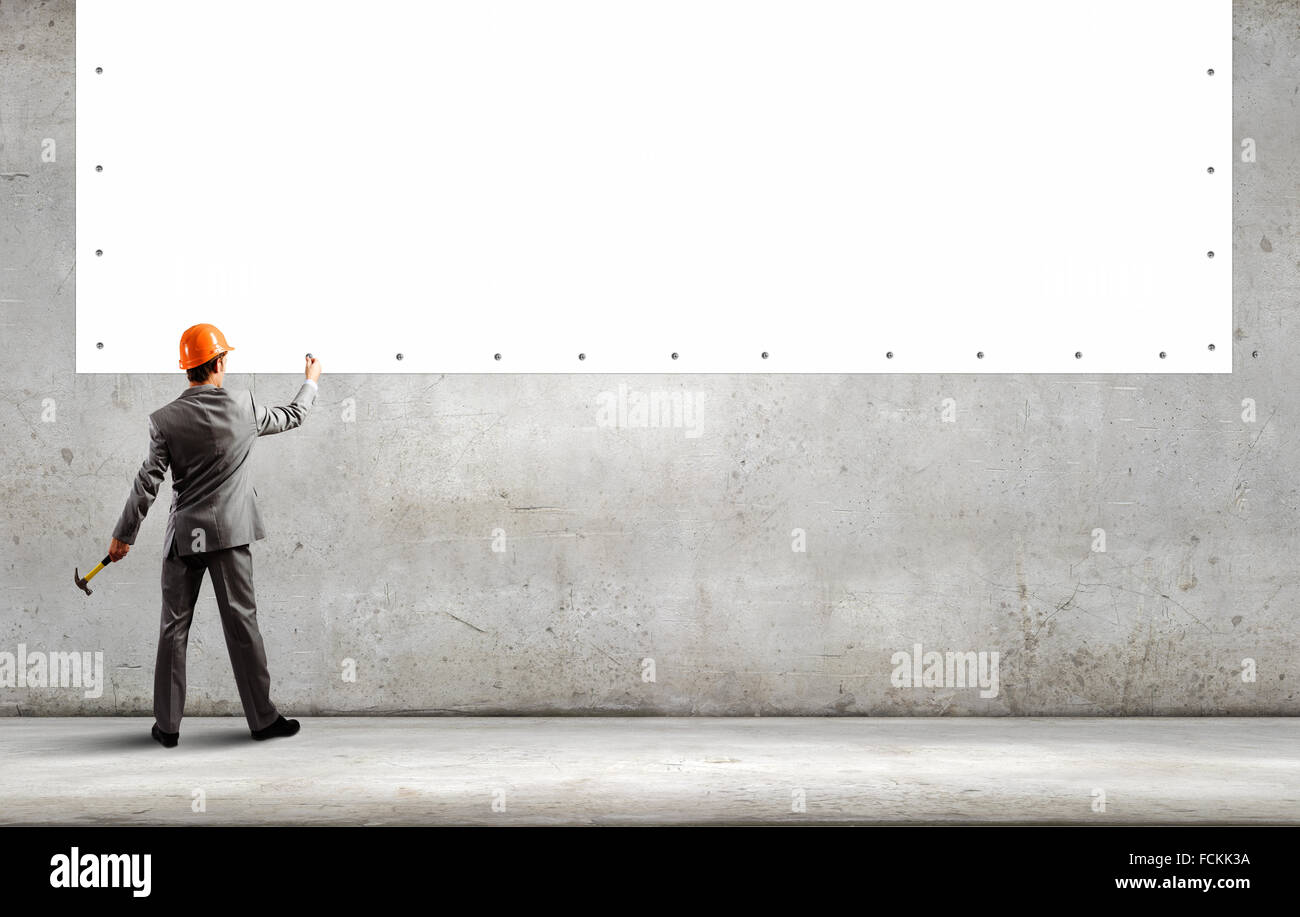 Rear view of businessman fixing white blank banner with hammer Stock ...