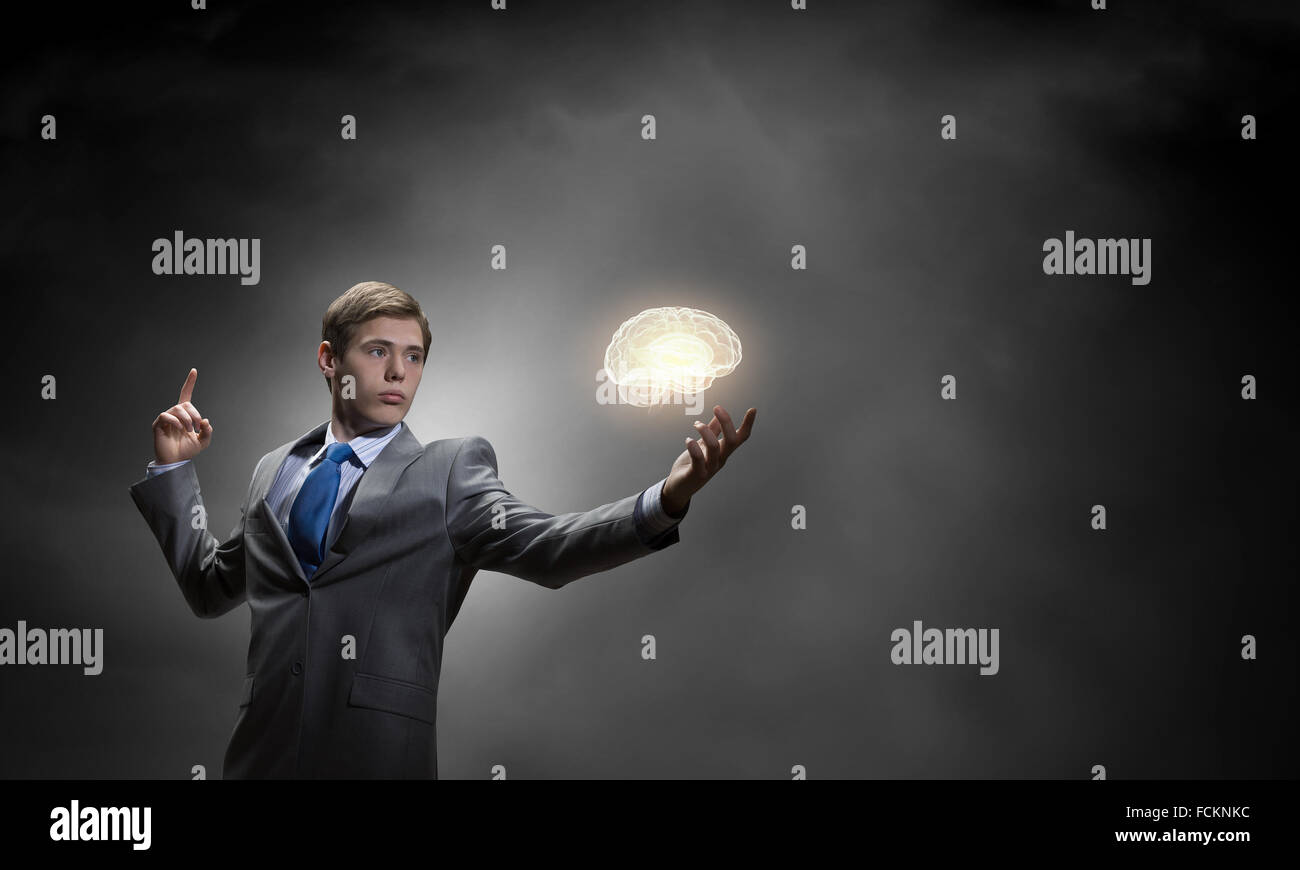 Young thoughtful businessman and human brain above his head Stock Photo ...