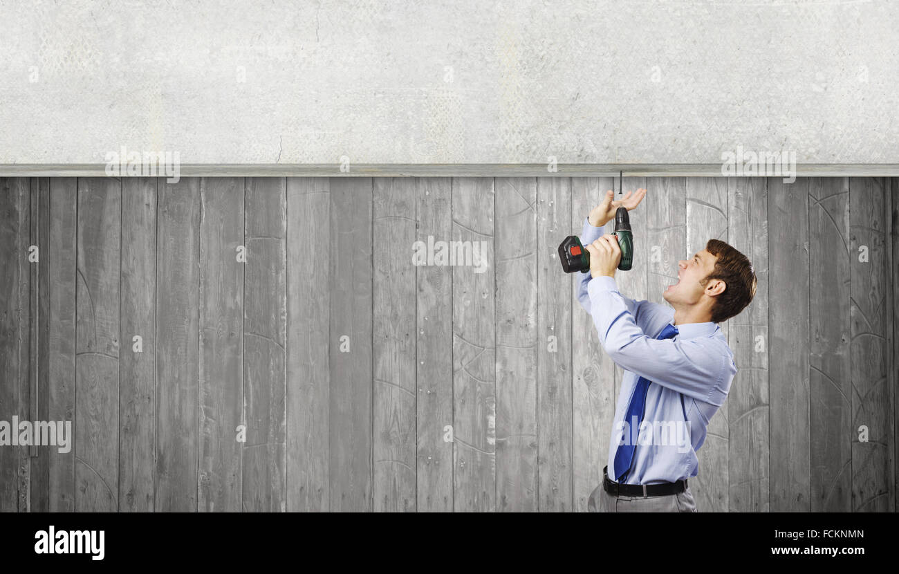 Young businessman using drill to fix banner Stock Photo - Alamy