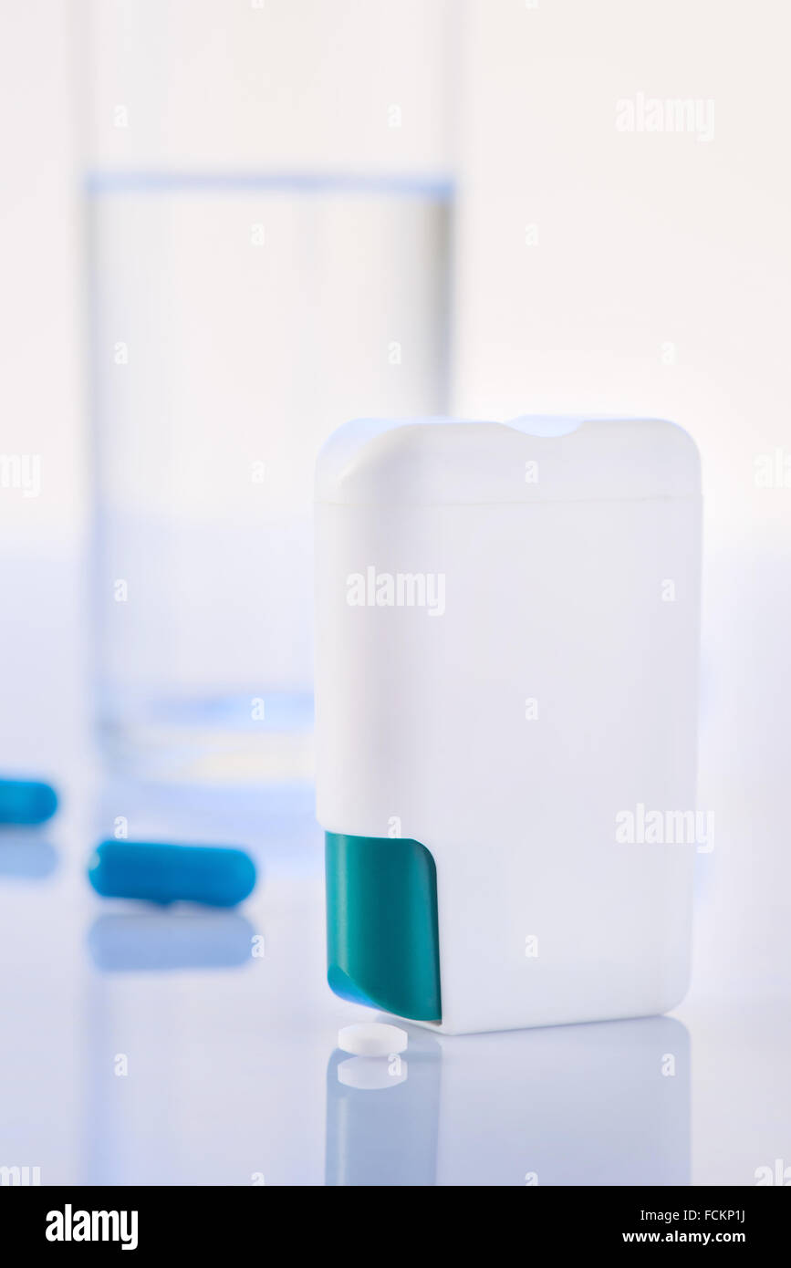 Pill dispenser and glass of water on the surface Stock Photo - Alamy