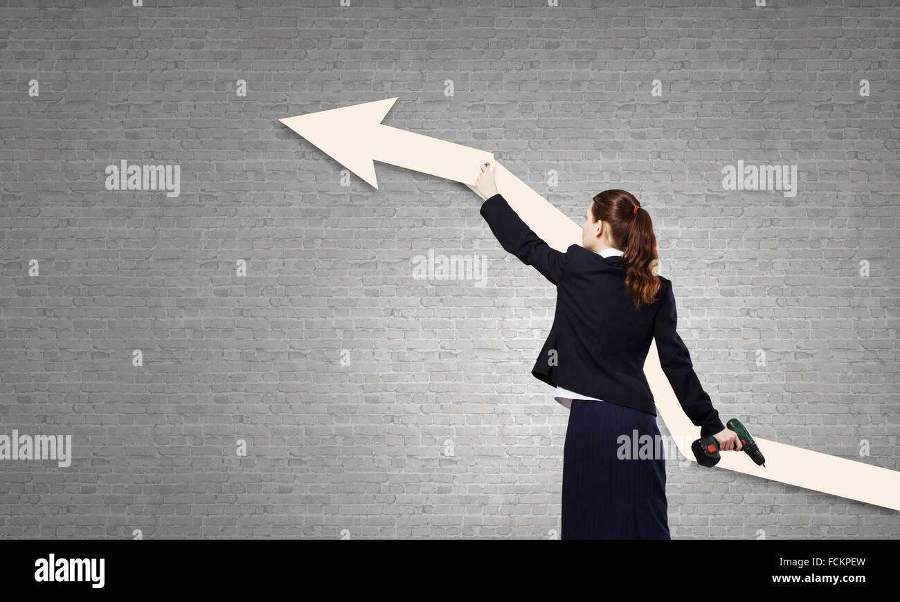 Young businesswoman fixing increasing arrow with drill Stock Photo - Alamy