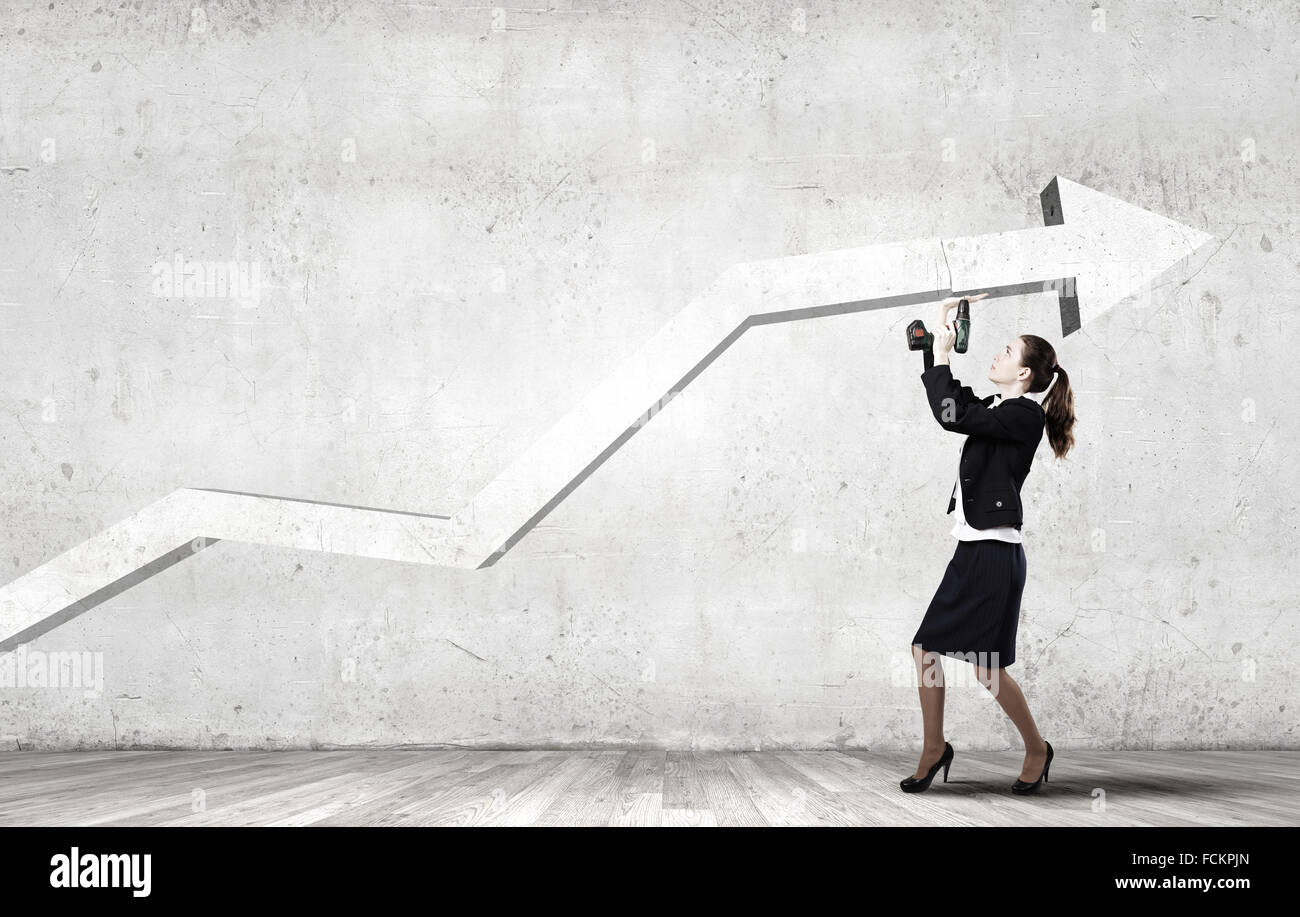 Young businesswoman fixing increasing arrow with drill Stock Photo - Alamy
