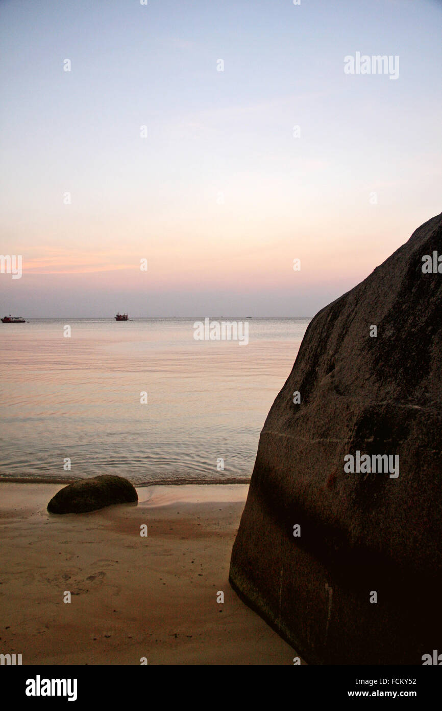 large boulder on a sandy beach in Thailand, sunset background and ...
