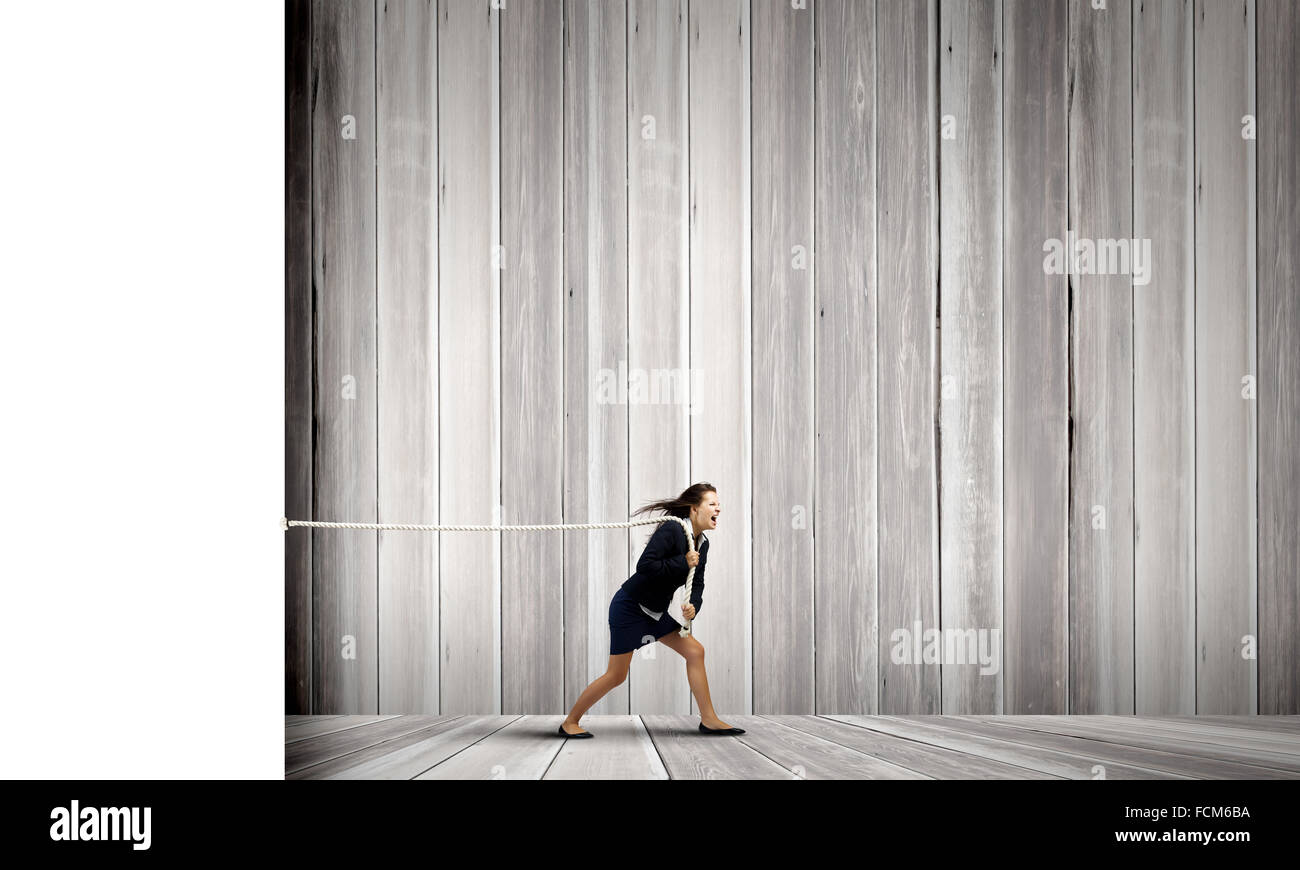 Young determined businesswoman pulling white blank banner with rope ...