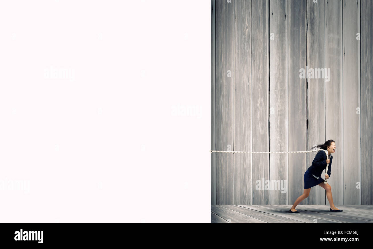 Young determined businesswoman pulling white blank banner with rope ...