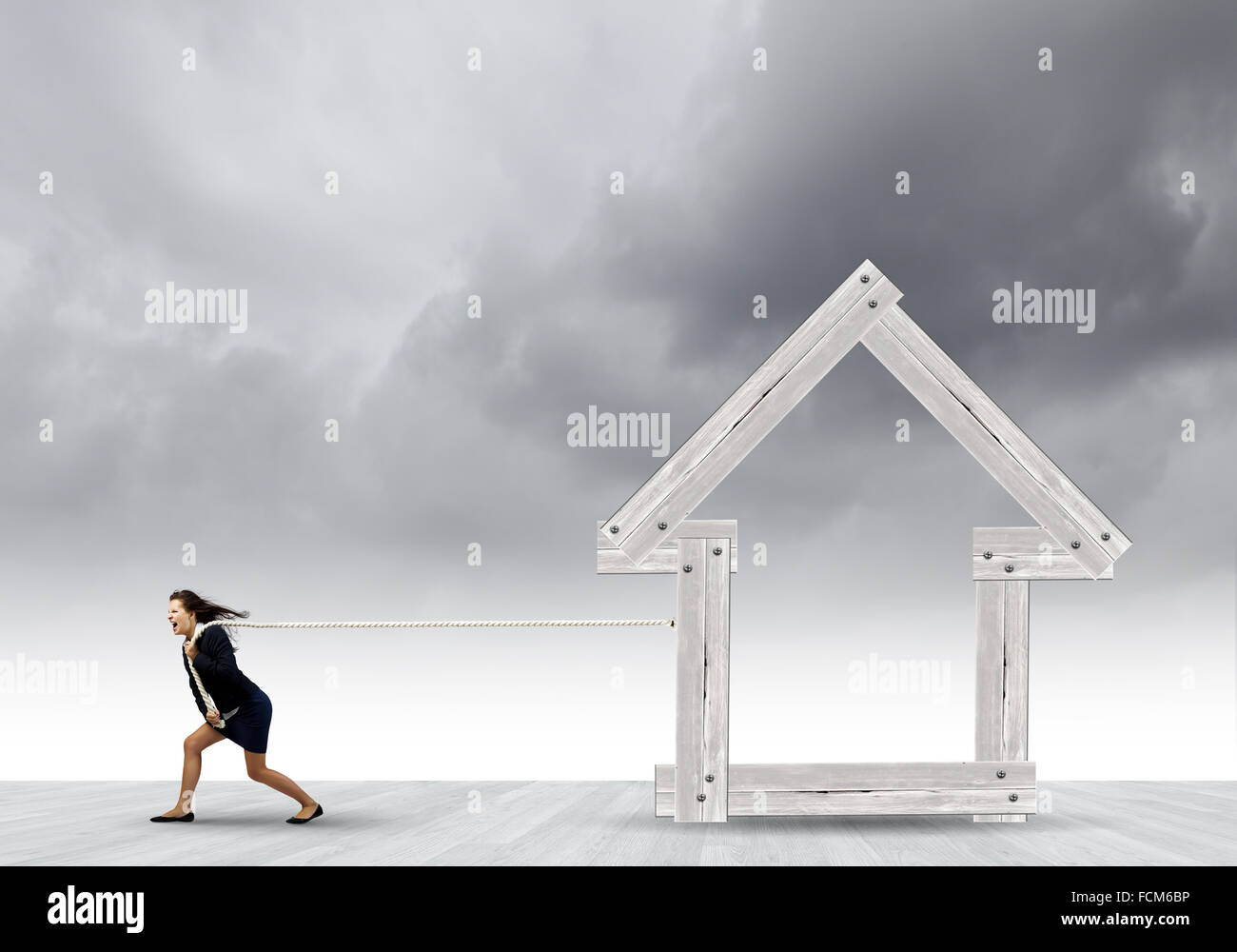 Young determined businesswoman pulling wooden house model Stock Photo ...