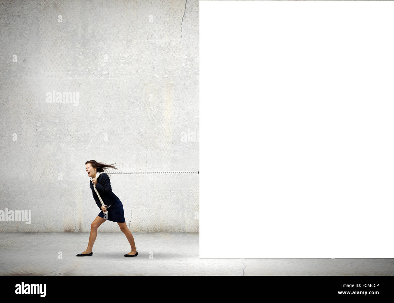 Young determined businesswoman pulling white blank banner with rope ...