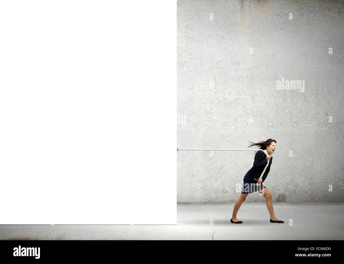 Young determined businesswoman pulling white blank banner with rope ...