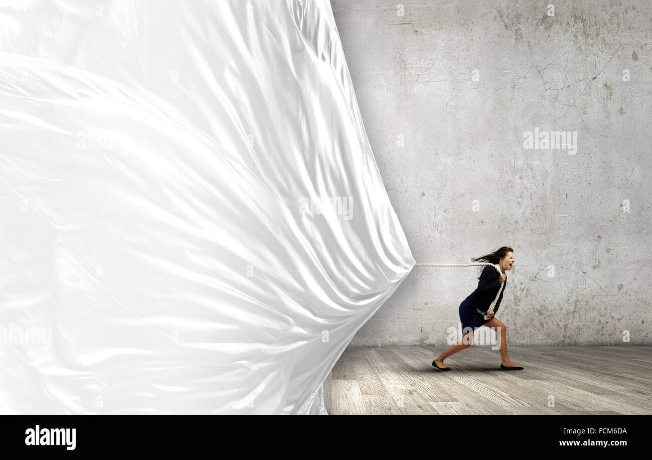 Young determined businesswoman pulling white blank banner with rope ...