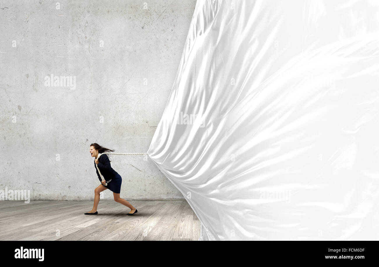Young determined businesswoman pulling white blank banner with rope ...