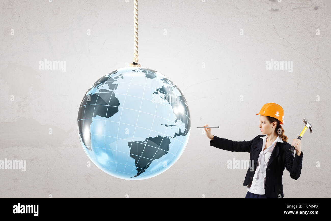 Woman builder hitting nail with hammer in digital globe Stock Photo - Alamy