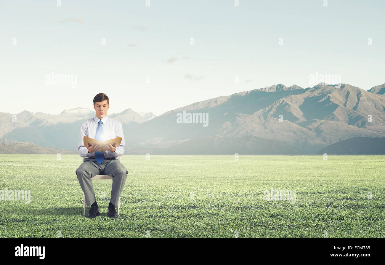 Businessman sitting in chair and reading book Stock Photo - Alamy
