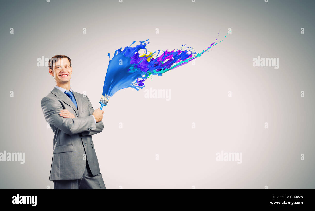 Young businessman holding paint brush with colorful splashes Stock ...