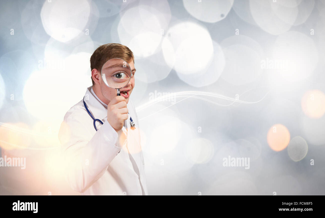 Funny young doctor with magnifier expecting something Stock Photo - Alamy