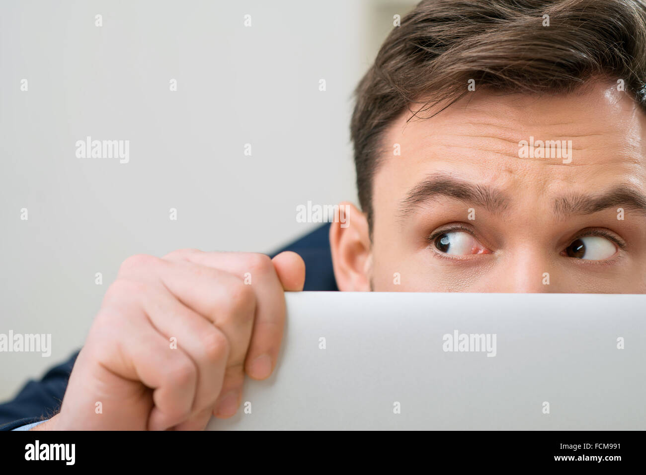 Pleasant office worker hiding behind laptop Stock Photo - Alamy