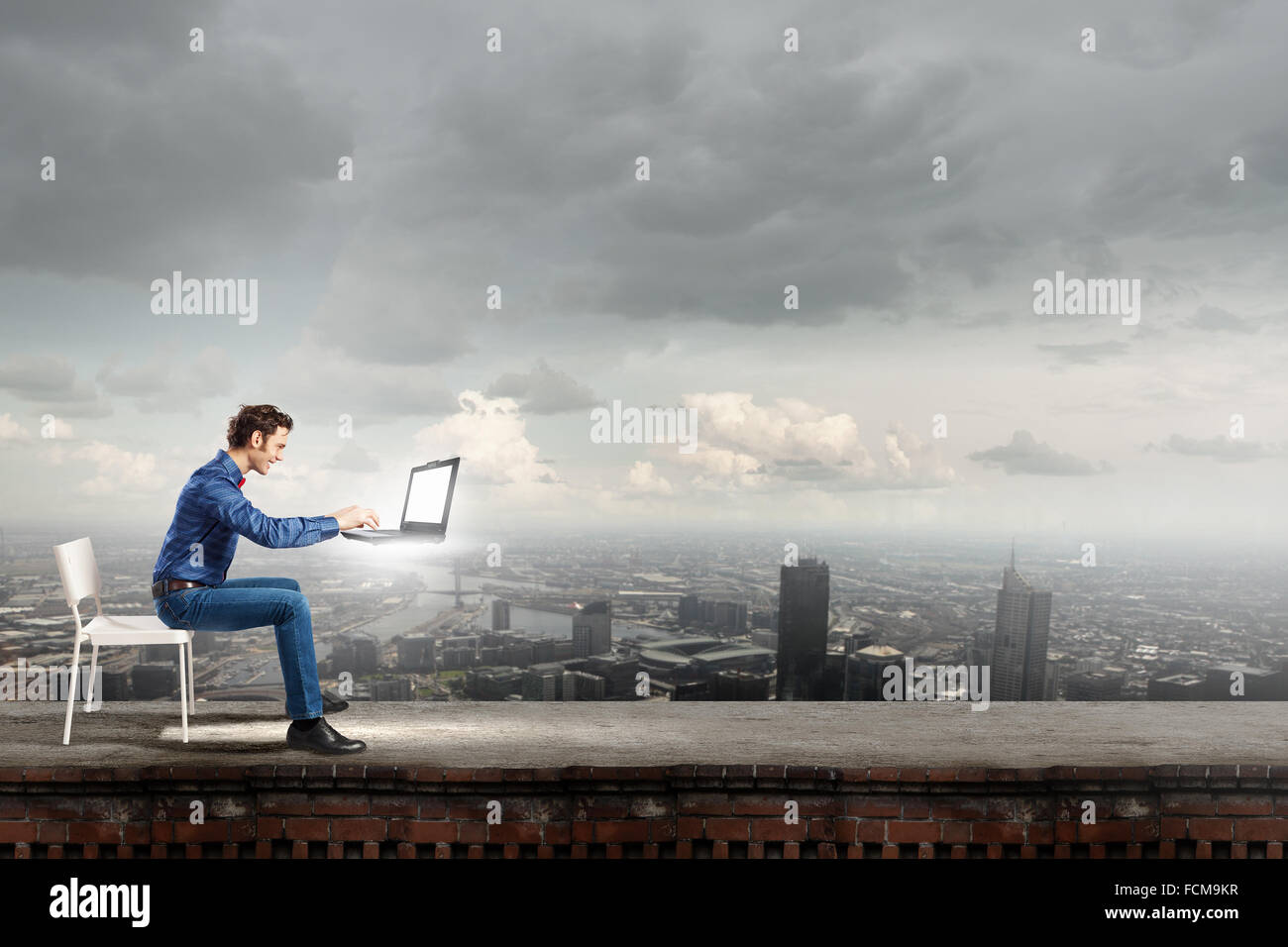Young man sitting in chair and using laptop Stock Photo - Alamy