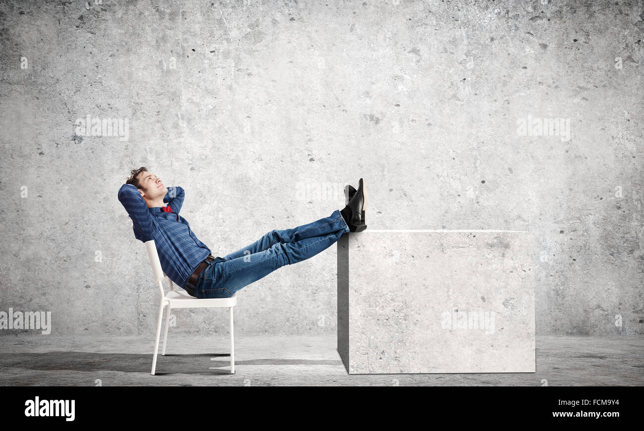 Young man sitting in chair with legs up and relaxing Stock Photo - Alamy