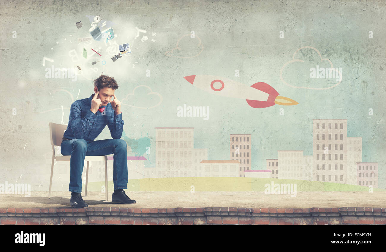 Troubled young man sitting in chair outdoors Stock Photo - Alamy