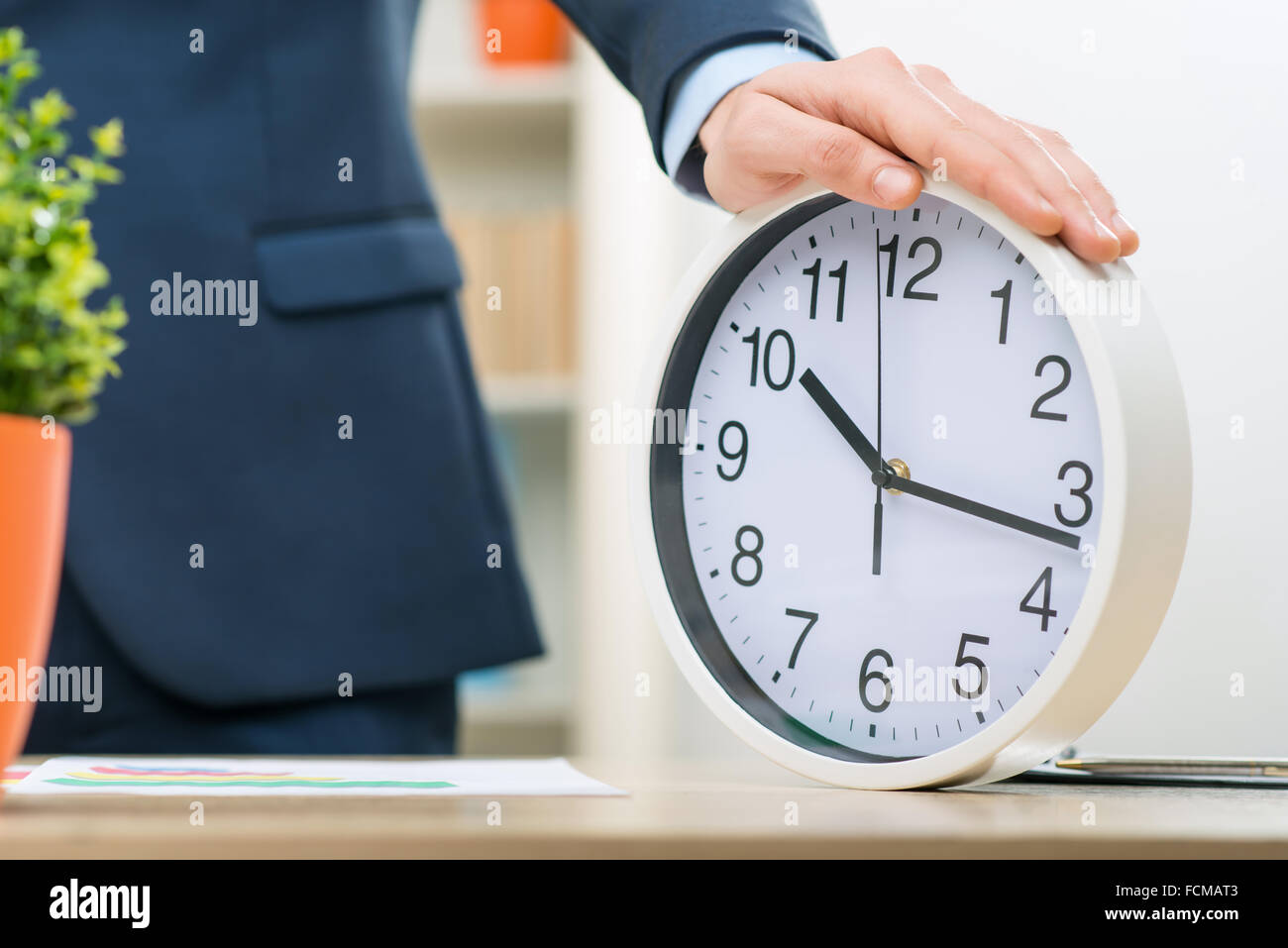 Pleasant office worker holding clock Stock Photo - Alamy