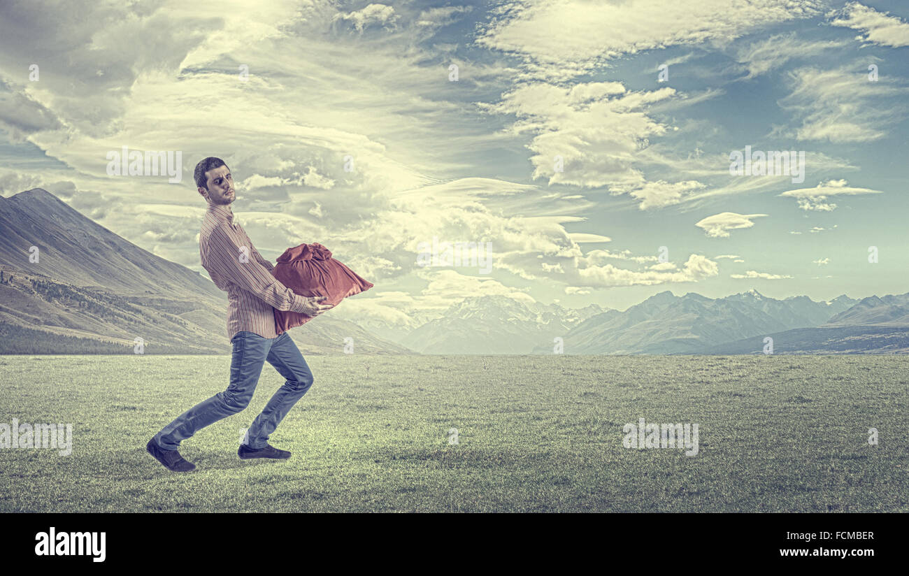 Young man in casual carrying heavy red bag Stock Photo - Alamy