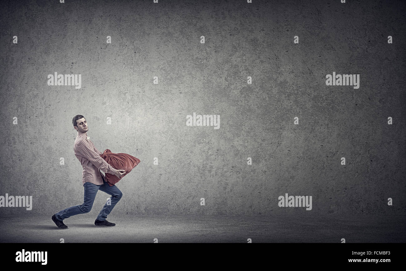 Young man in casual carrying heavy red bag Stock Photo - Alamy