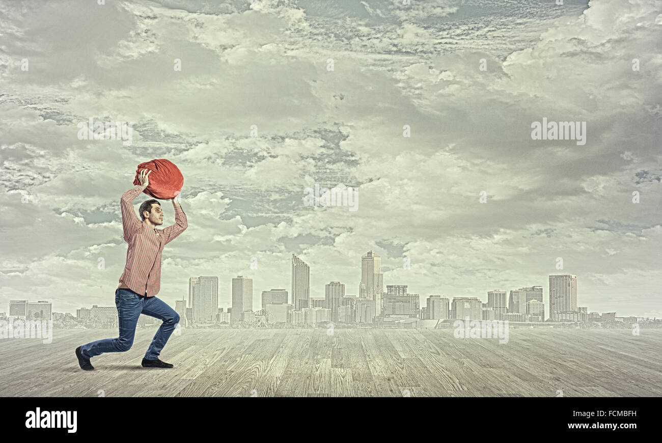 Young man in casual carrying heavy red bag Stock Photo - Alamy