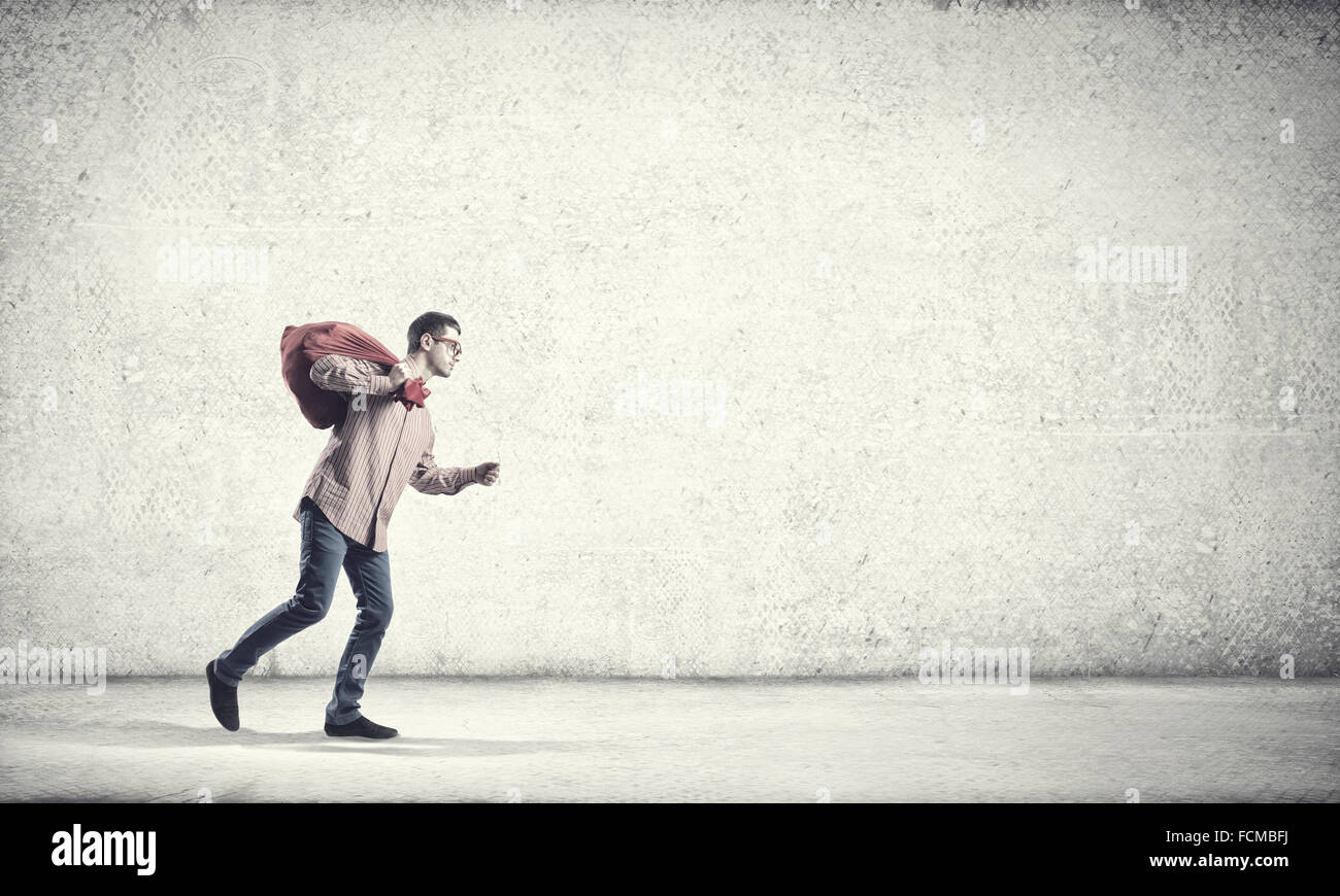 Young man in casual carrying heavy red bag Stock Photo - Alamy