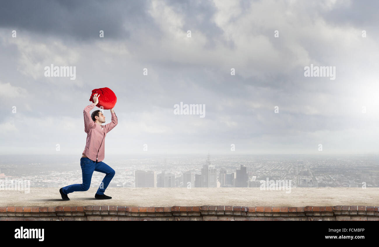 Young man in casual carrying heavy red bag Stock Photo - Alamy