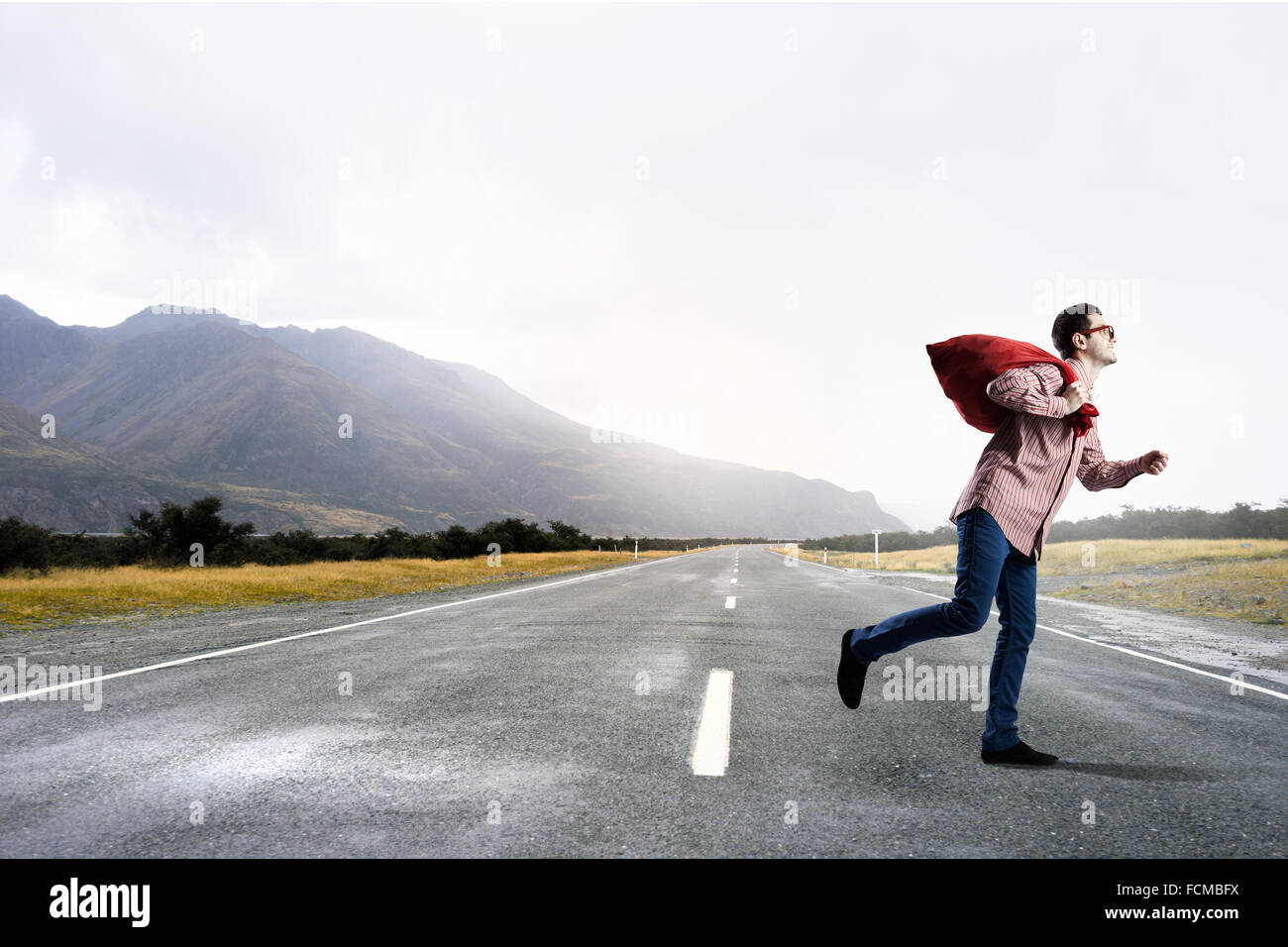 Young man in casual carrying heavy red bag Stock Photo - Alamy