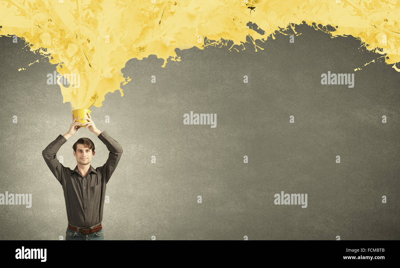 Young man in casual splashing paint from bucket Stock Photo - Alamy