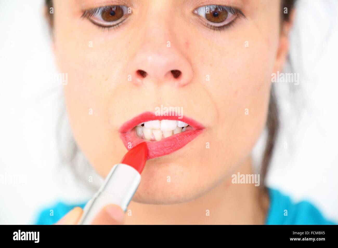 Girl painting her lips with eyes looking down Stock Photo - Alamy