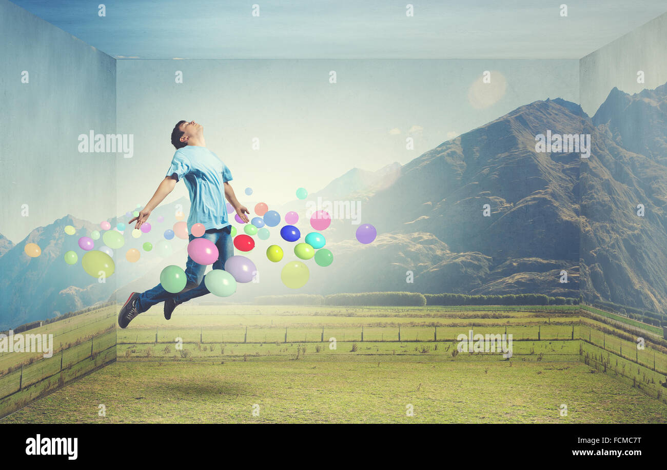 Young man jumping in sky among colorful balloons Stock Photo - Alamy