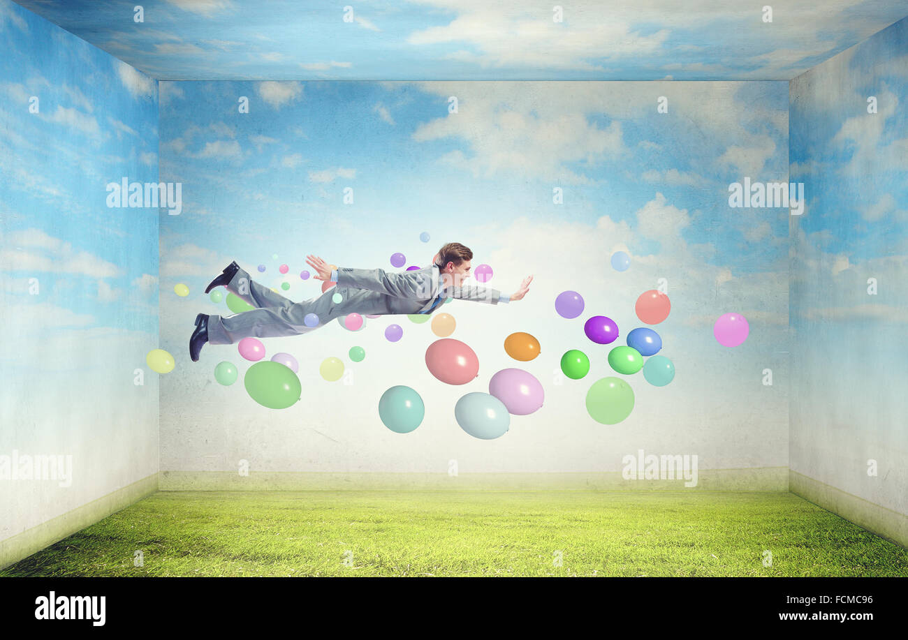 Young man flying in sky among colorful balloons Stock Photo - Alamy