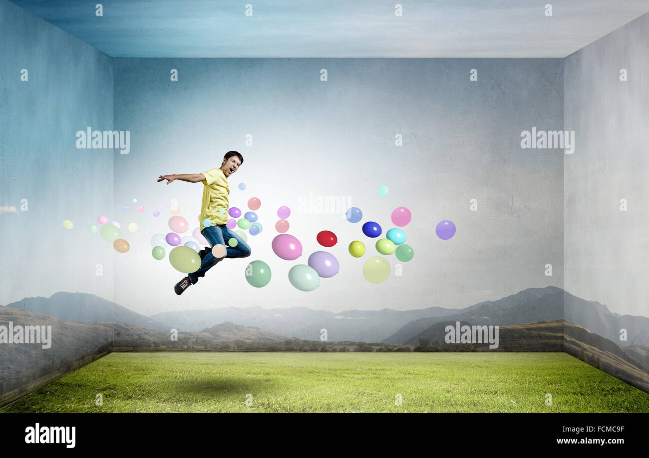 Young man jumping in sky among colorful balloons Stock Photo - Alamy