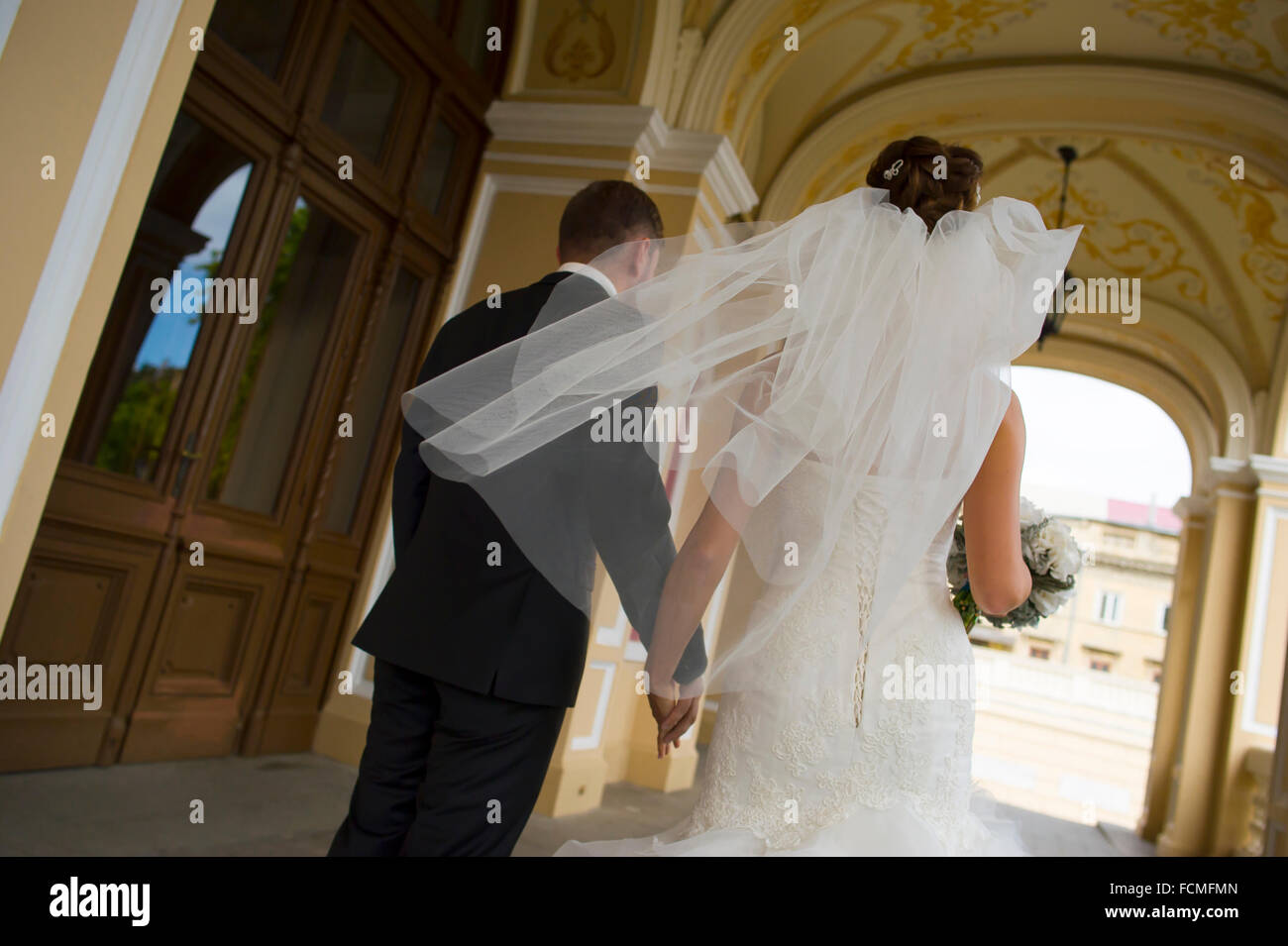 The newlyweds are walking under church arches Stock Photo - Alamy