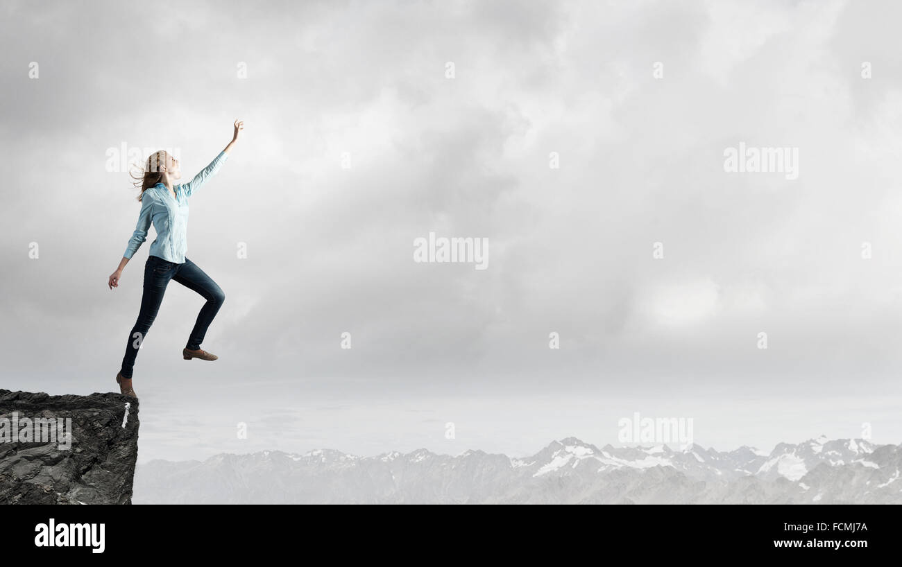 Young woman on rock edge making step above gap Stock Photo - Alamy