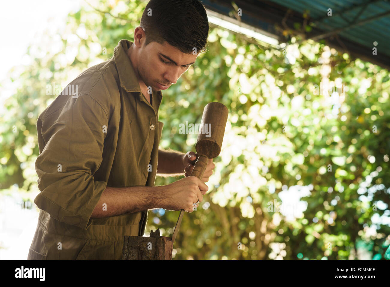 Young man at work learning craftsman profession, working with hammer ...