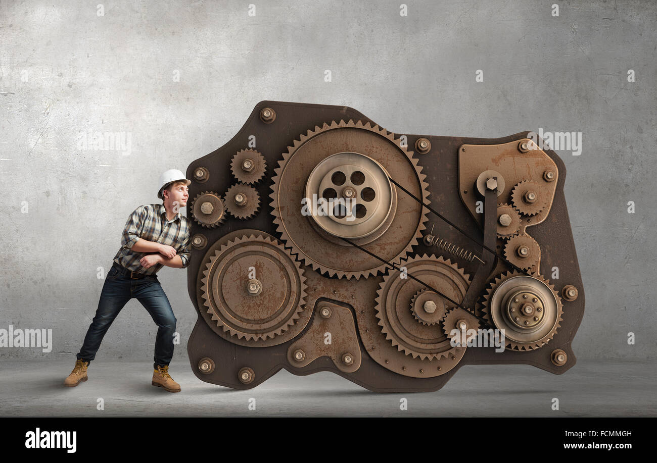 Man builder trying to move big cogwheels mechanism Stock Photo - Alamy