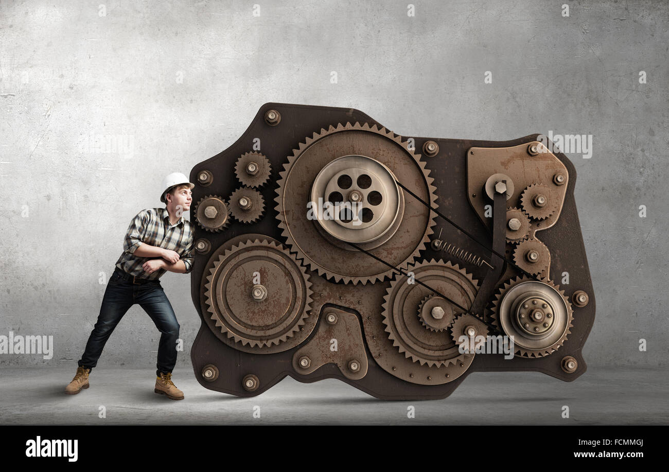 Man builder trying to move big cogwheels mechanism Stock Photo - Alamy