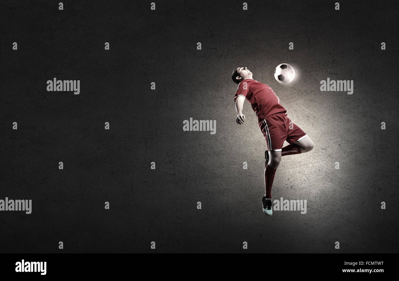 Football player in red shirt jump taking ball Stock Photo - Alamy