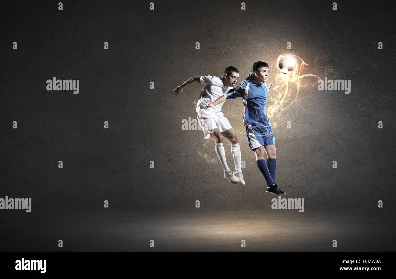 Two football players in jump fighting for ball Stock Photo - Alamy