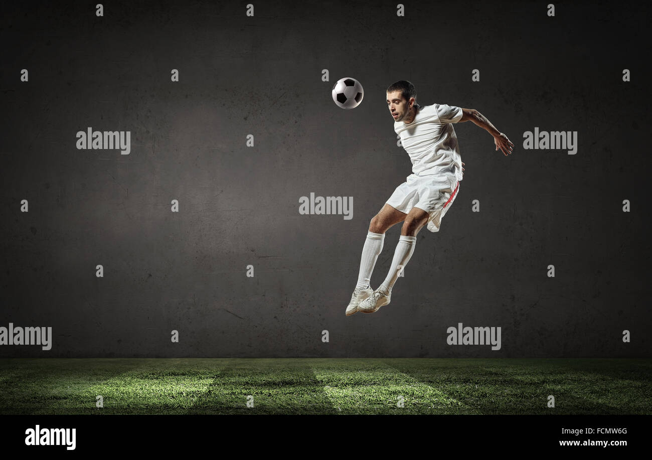 Football player in red shirt jump taking ball Stock Photo - Alamy