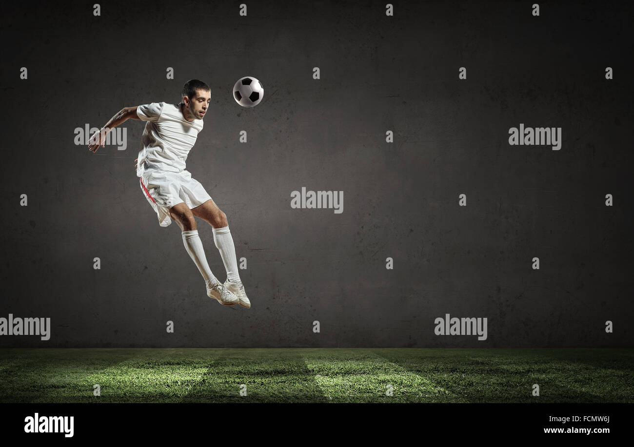 Football player in red shirt jump taking ball Stock Photo - Alamy
