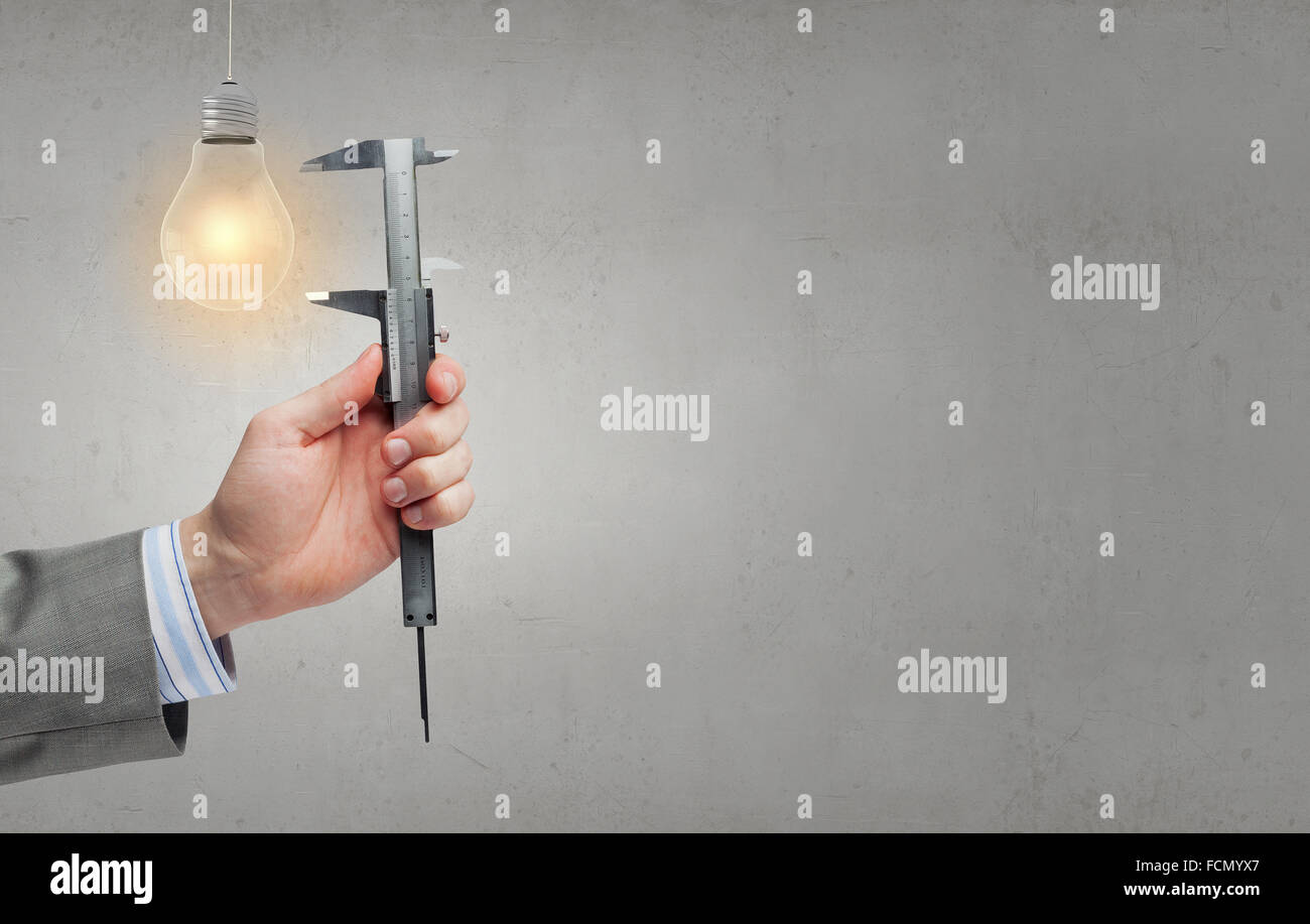 Close up of hand measuring light bulb with wrench Stock Photo - Alamy