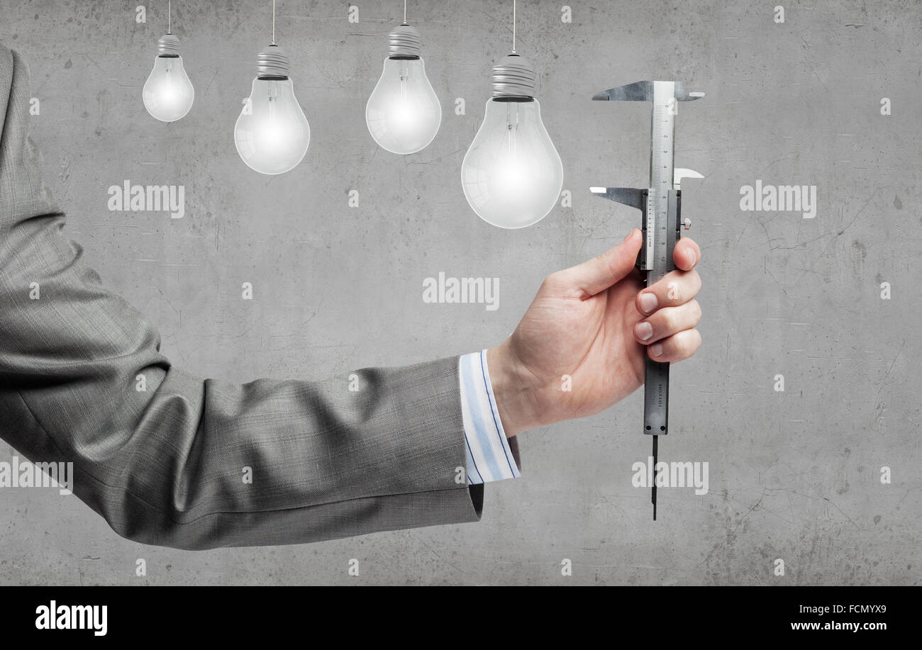 Close up of hand measuring light bulb with wrench Stock Photo - Alamy