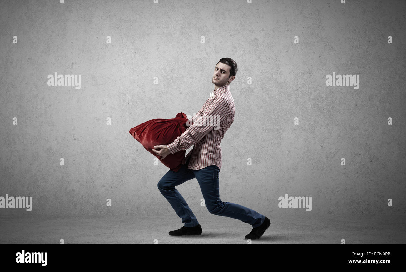 Young man in casual carrying heavy red bag Stock Photo - Alamy