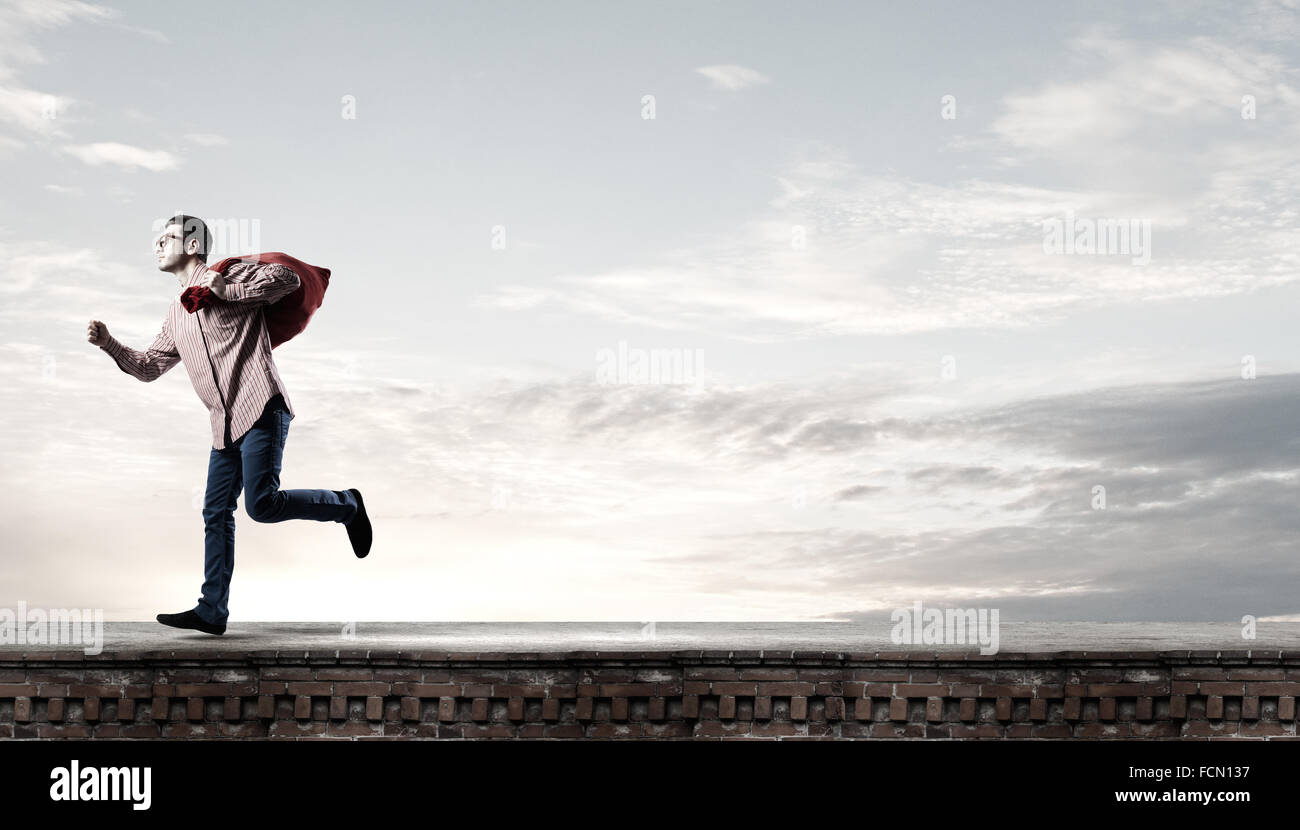 Young man in casual carrying heavy red bag Stock Photo - Alamy
