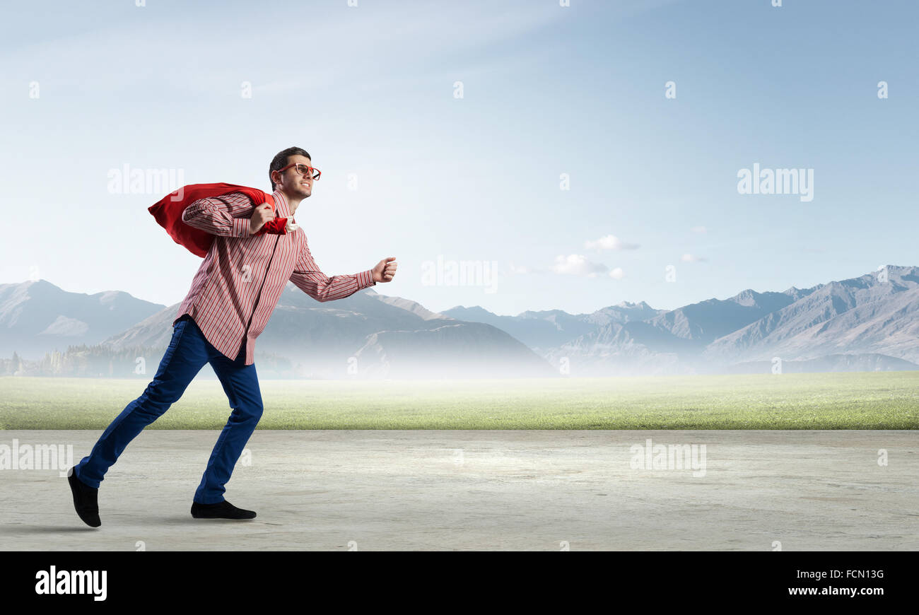 Young man in casual carrying heavy red bag Stock Photo - Alamy