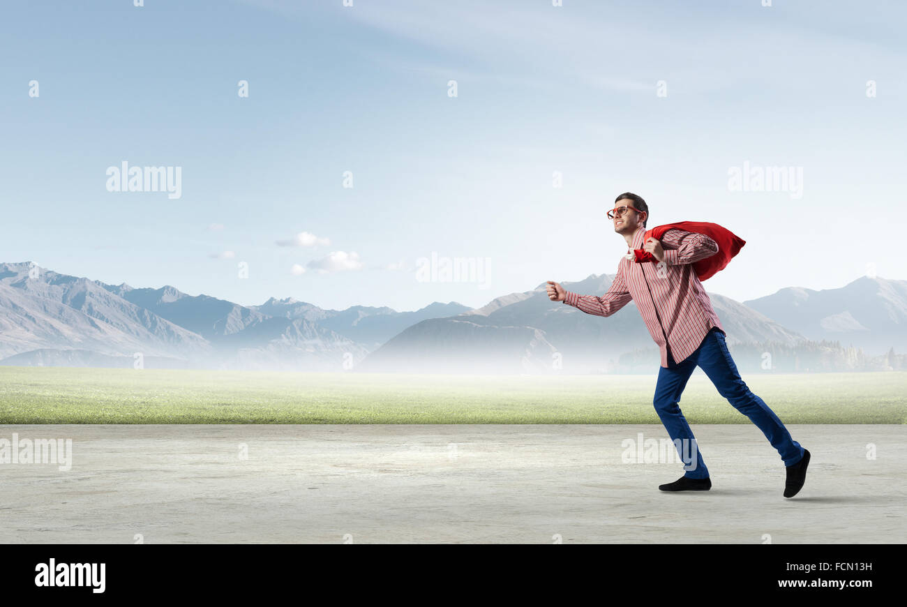 Young man in casual carrying heavy red bag Stock Photo - Alamy