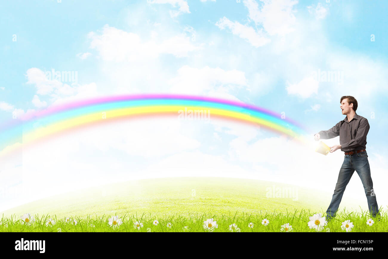 Young man in casual splashing rainbow from bucket Stock Photo - Alamy
